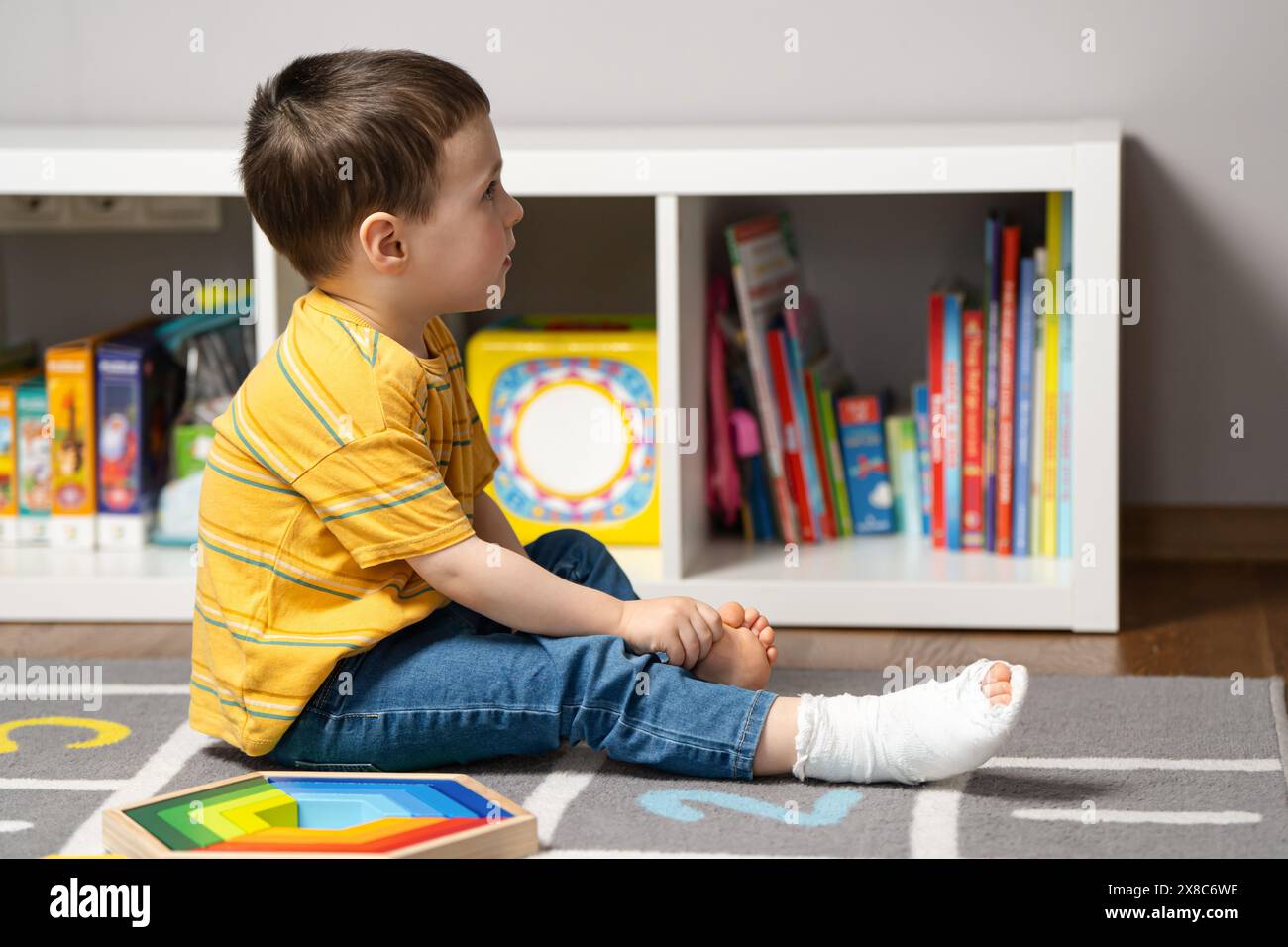 A little toddler boy 3 years sitting with a cast in a leg in a children ...