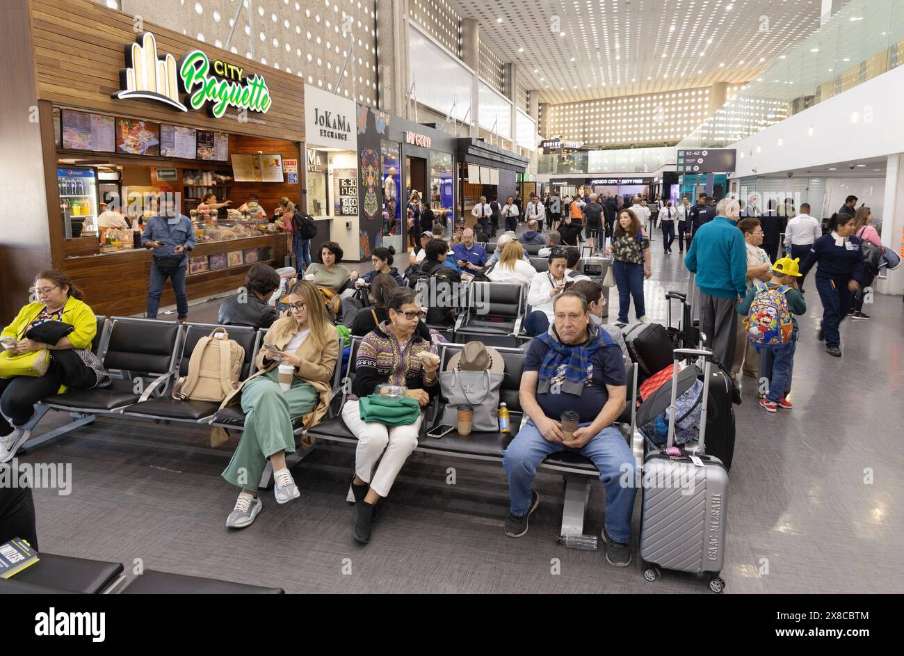 Airport passengers sitting waiting for their flight inside the Terminal; Mexico City ...