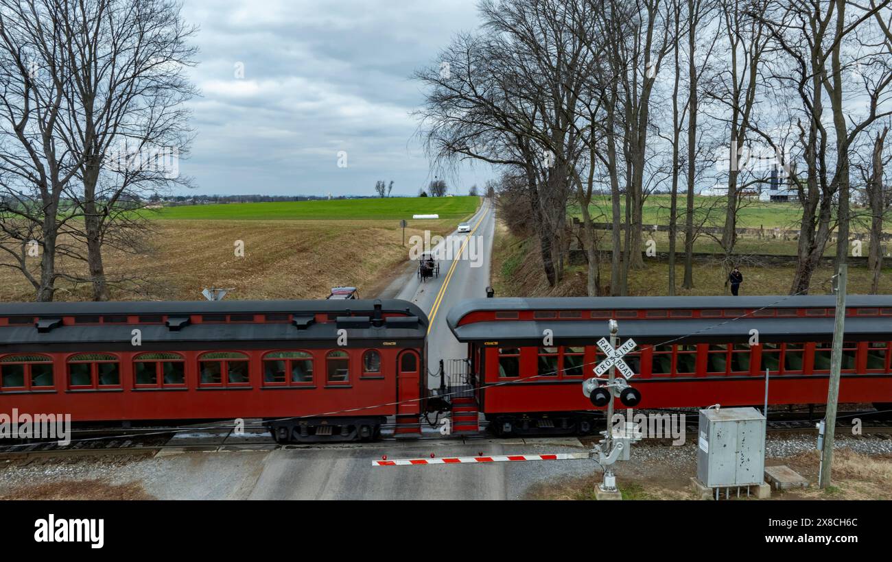 A Historic Train Crossing Rural Road with an Amish Horse-Drawn Carriage ...