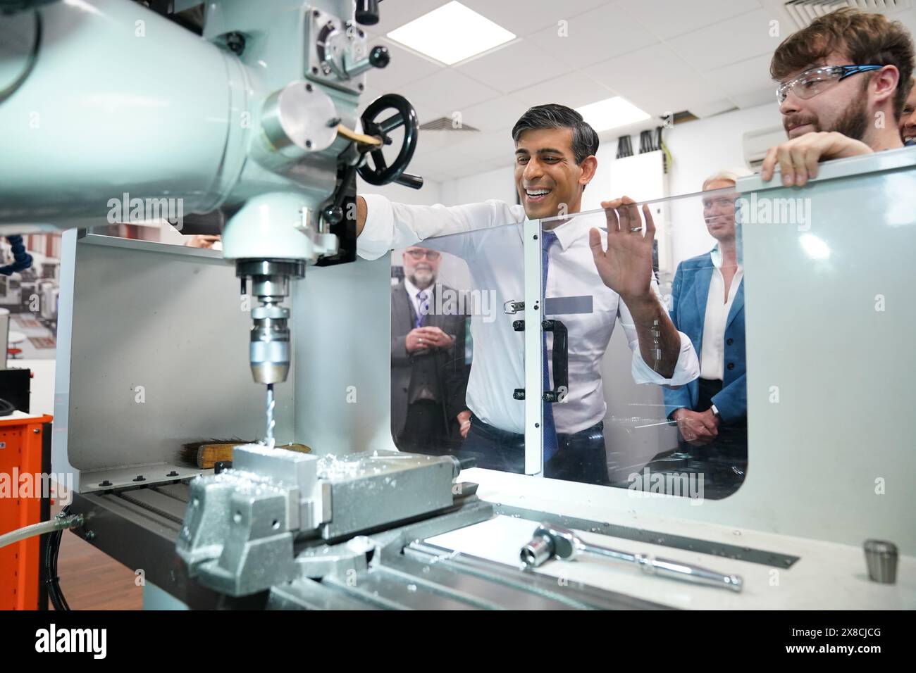 Prime Minister Rishi Sunak attempts to drill a hole in a piece of metal ...