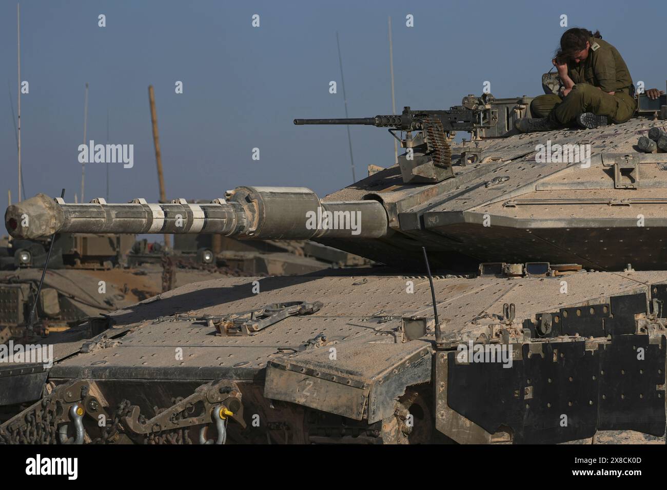 An Israeli female soldier sits atop a tank in a staging area near the ...