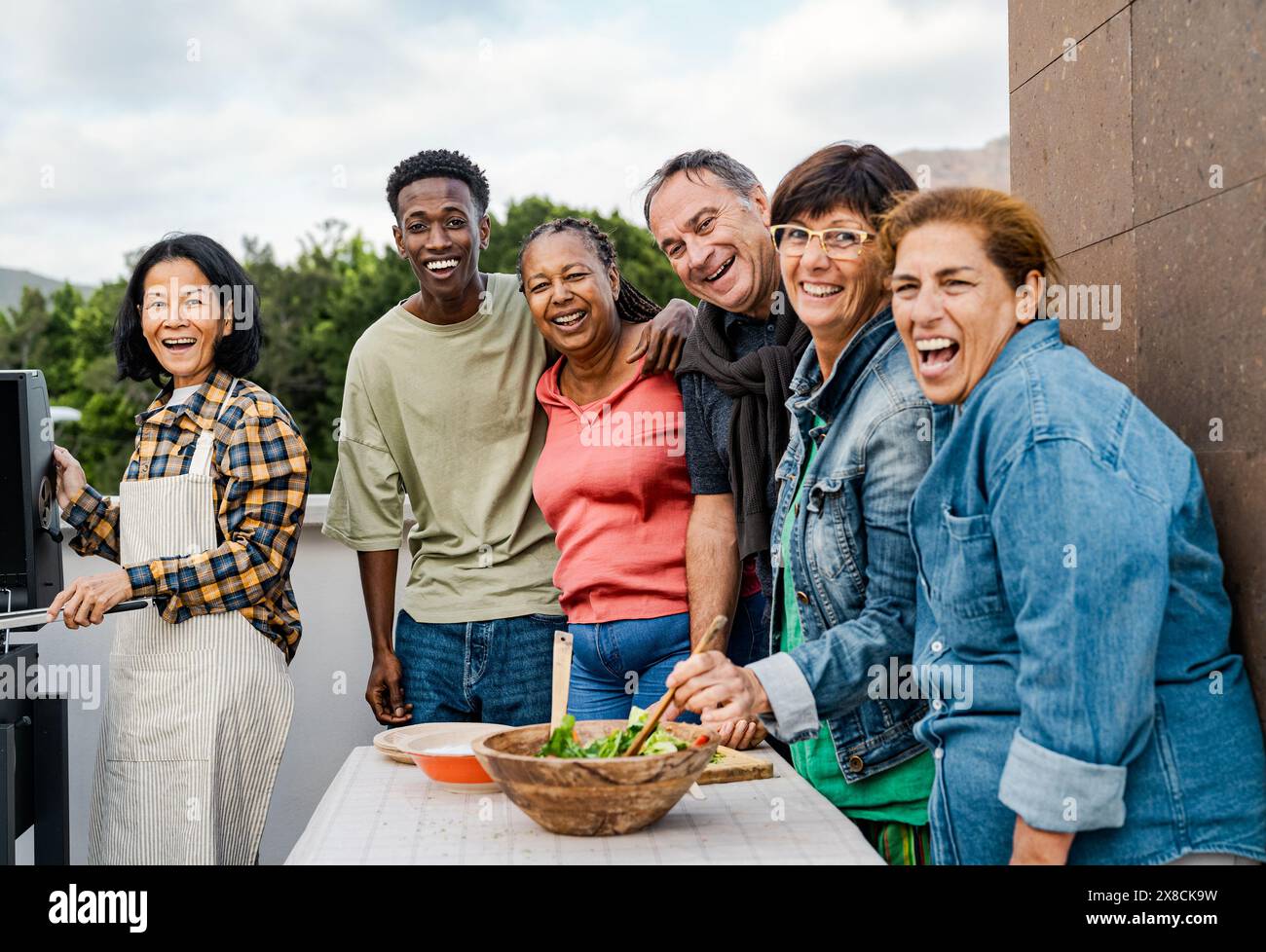 Happy multigenerational friends having fun preparing food at house ...