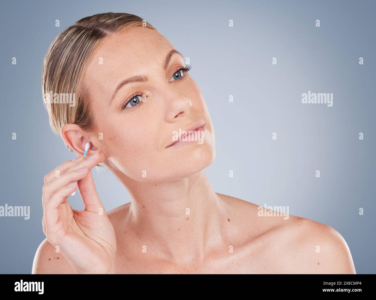 Woman, cleaning and ear for hygiene in studio for personal self care ...
