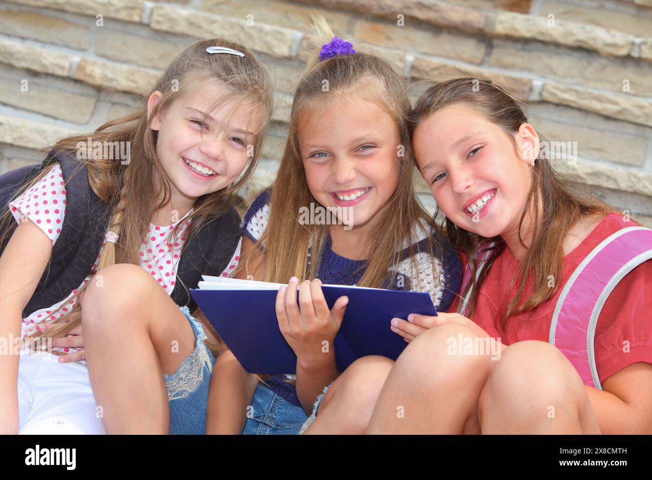 cheerful elementary school girls reeding notebook studying sitting on ...