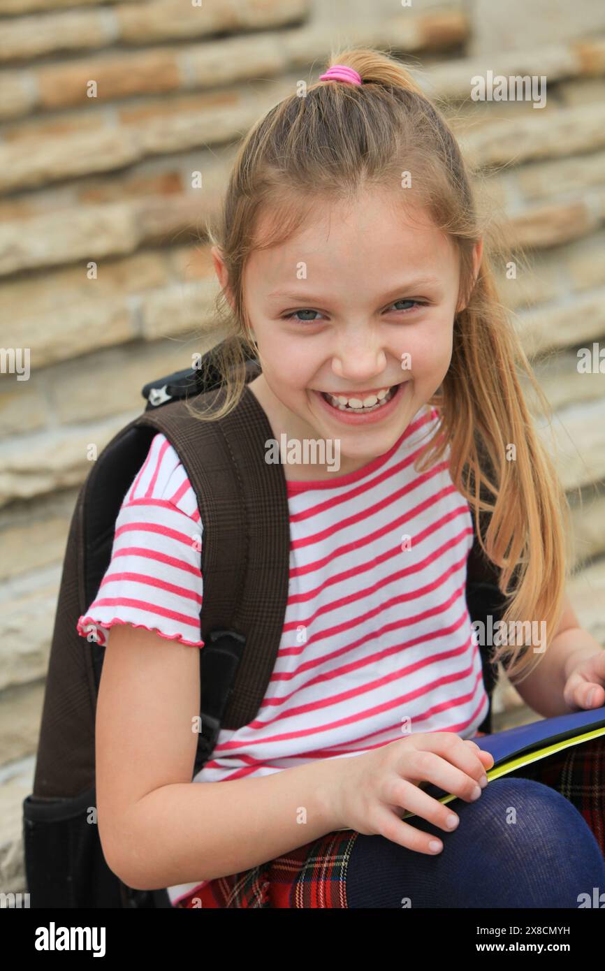 cheerful elementary schoolgirl on white background Stock Photo - Alamy