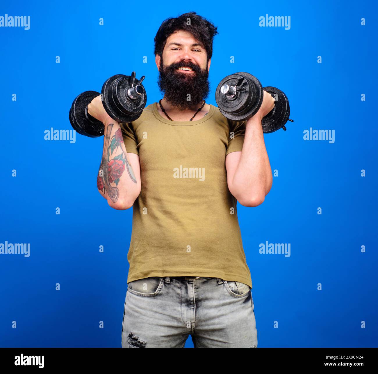 Strong smiling bearded sportsman training with dumbbells. Bodybuilder ...