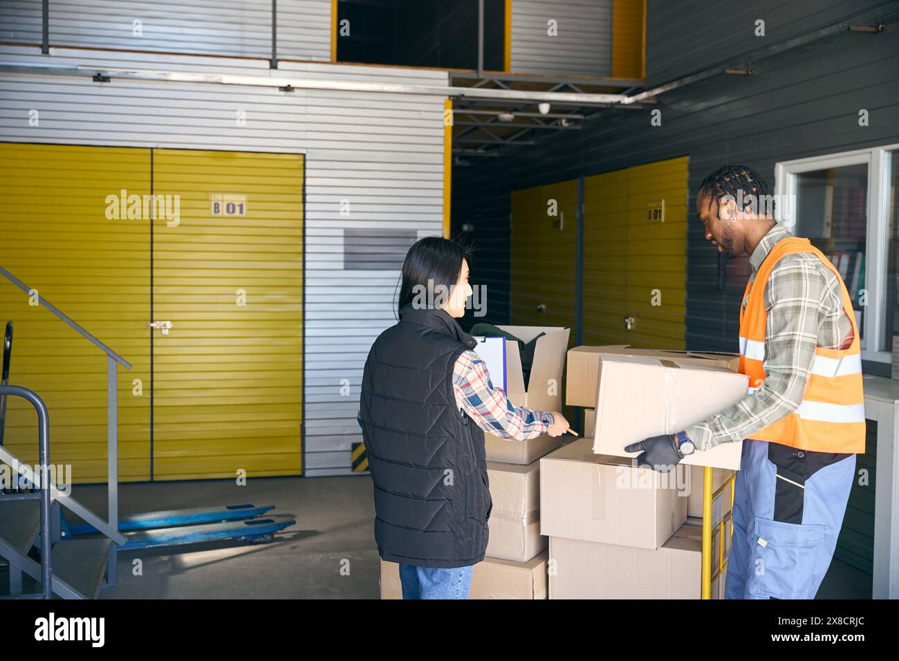 Freight handler unloading goods supervised by coworker in storehouse ...