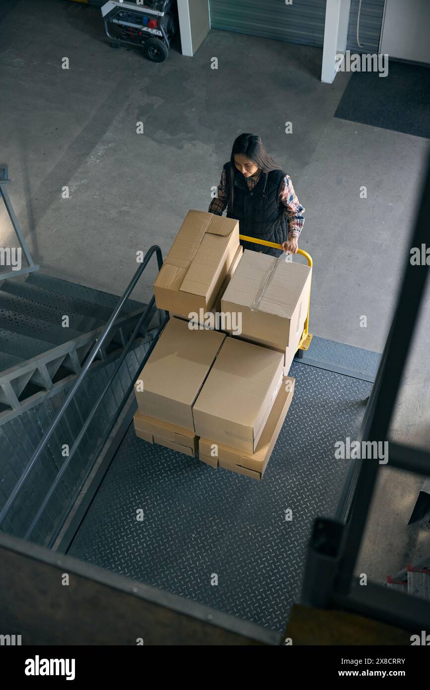 Freight handler transporting goods on wheeled cart in warehouse ...