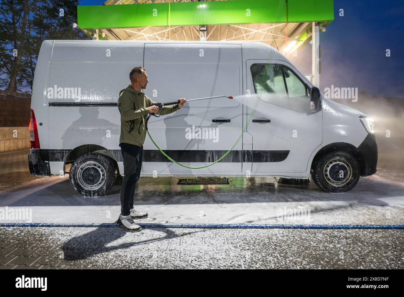 Man Pressure Washing and Cleaning Modern White Van During Late Evening ...