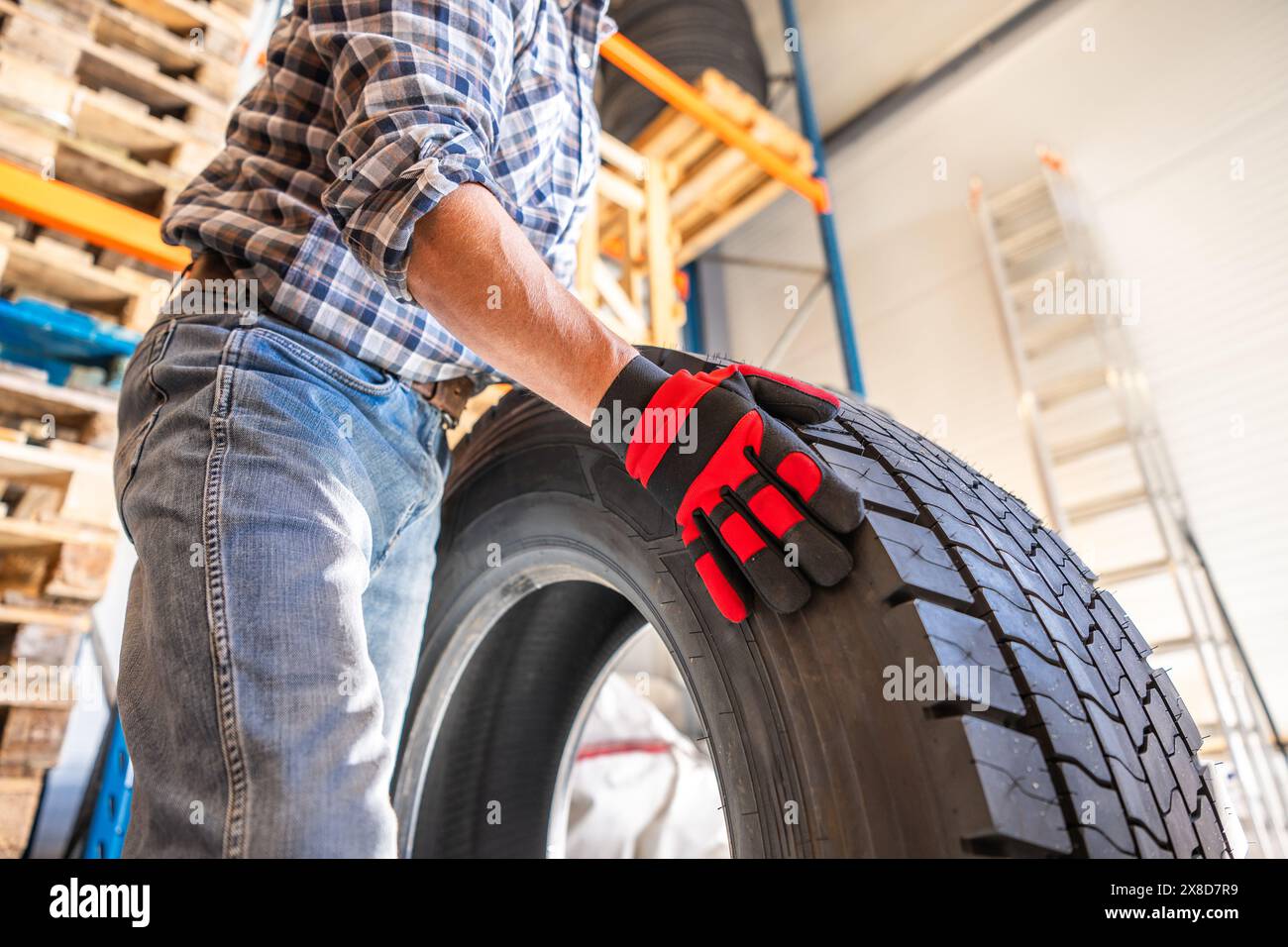 A worker wearing work clothes stands in a warehouse, holding a large ...