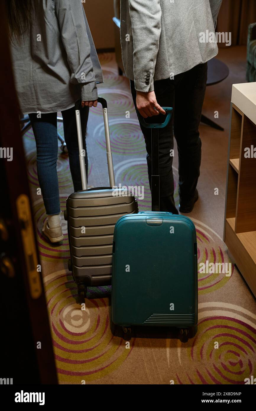 Two people with wheeled luggage checking into hotel room Stock Photo ...