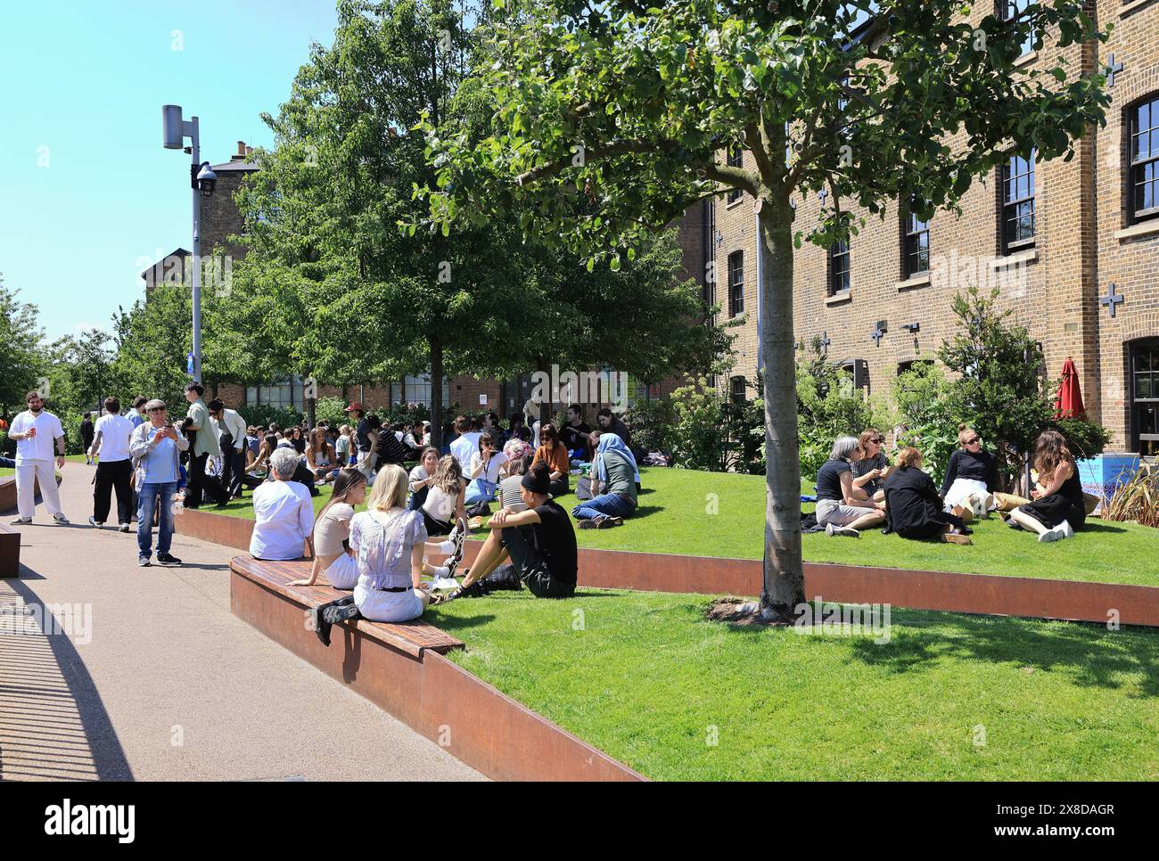 Workers relaxing in Wharf Gardens by Granary Square, in late spring ...