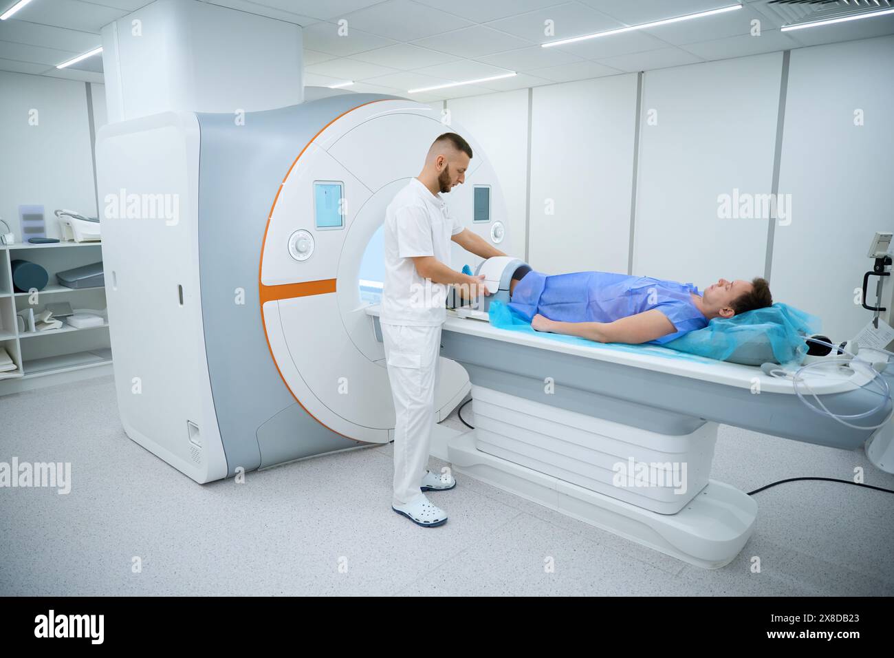 Medical professional preparing man for MRI of lower limb joint Stock ...