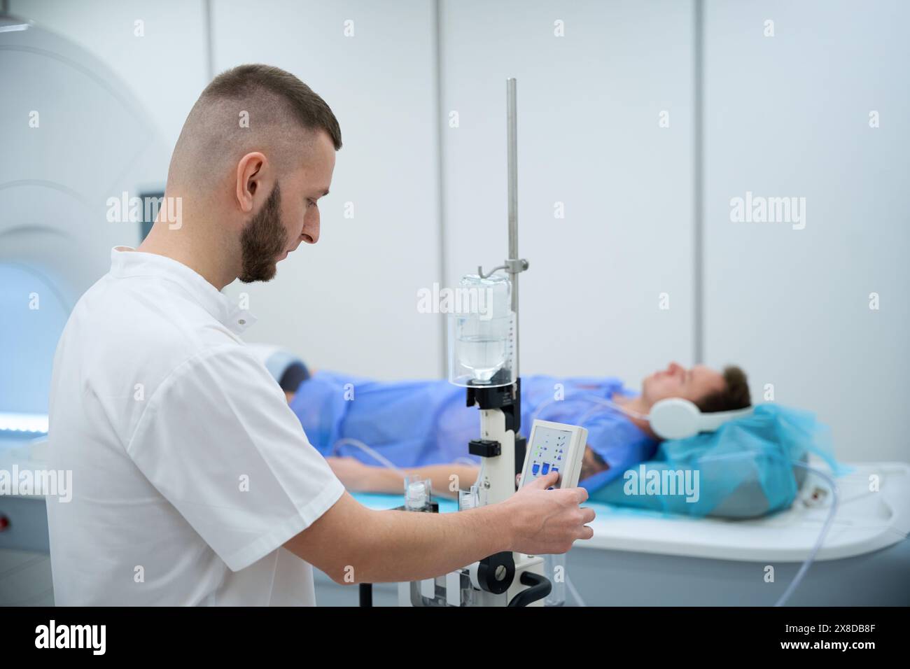 Radiographer preparing patient for contrast-enhanced MRI of lower ...