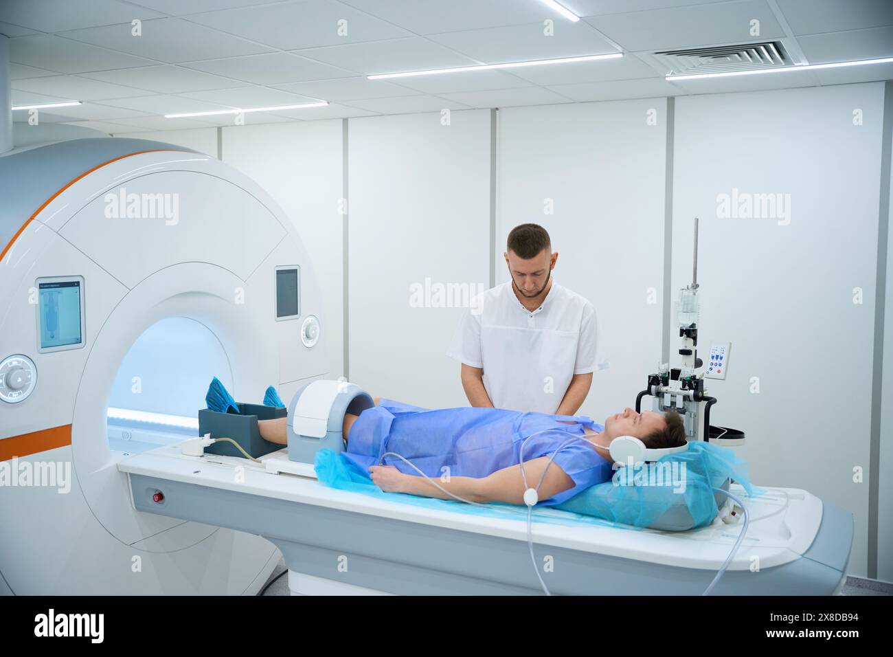 Technologist preparing man for magnetic resonance imaging of lower ...