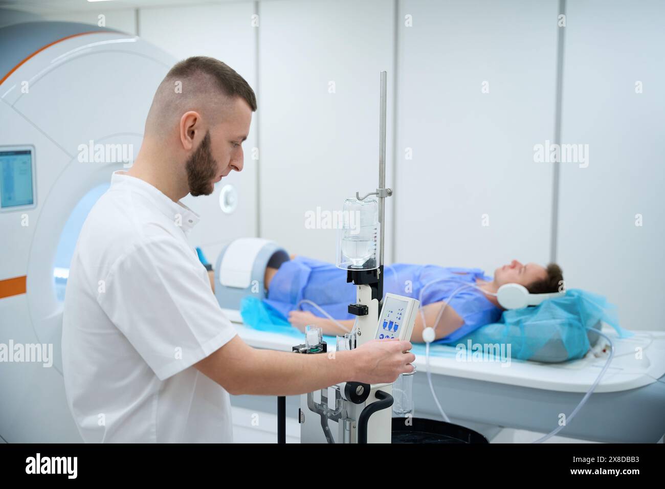 Doctor preparing man for contrast-enhanced lower extremity joint MRI ...