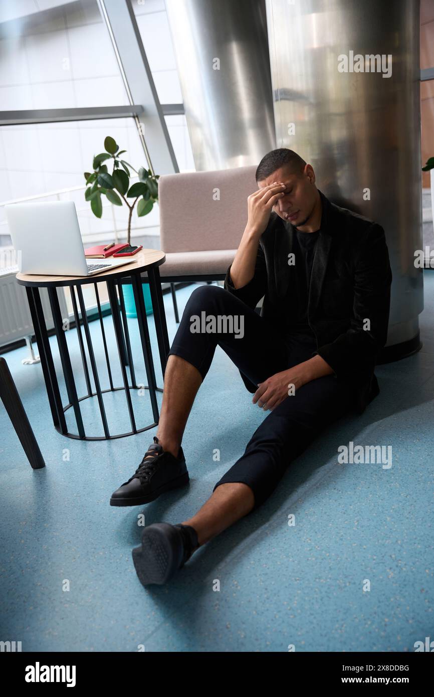Depressed man sitting on floor while pressing fingers to forehead Stock ...