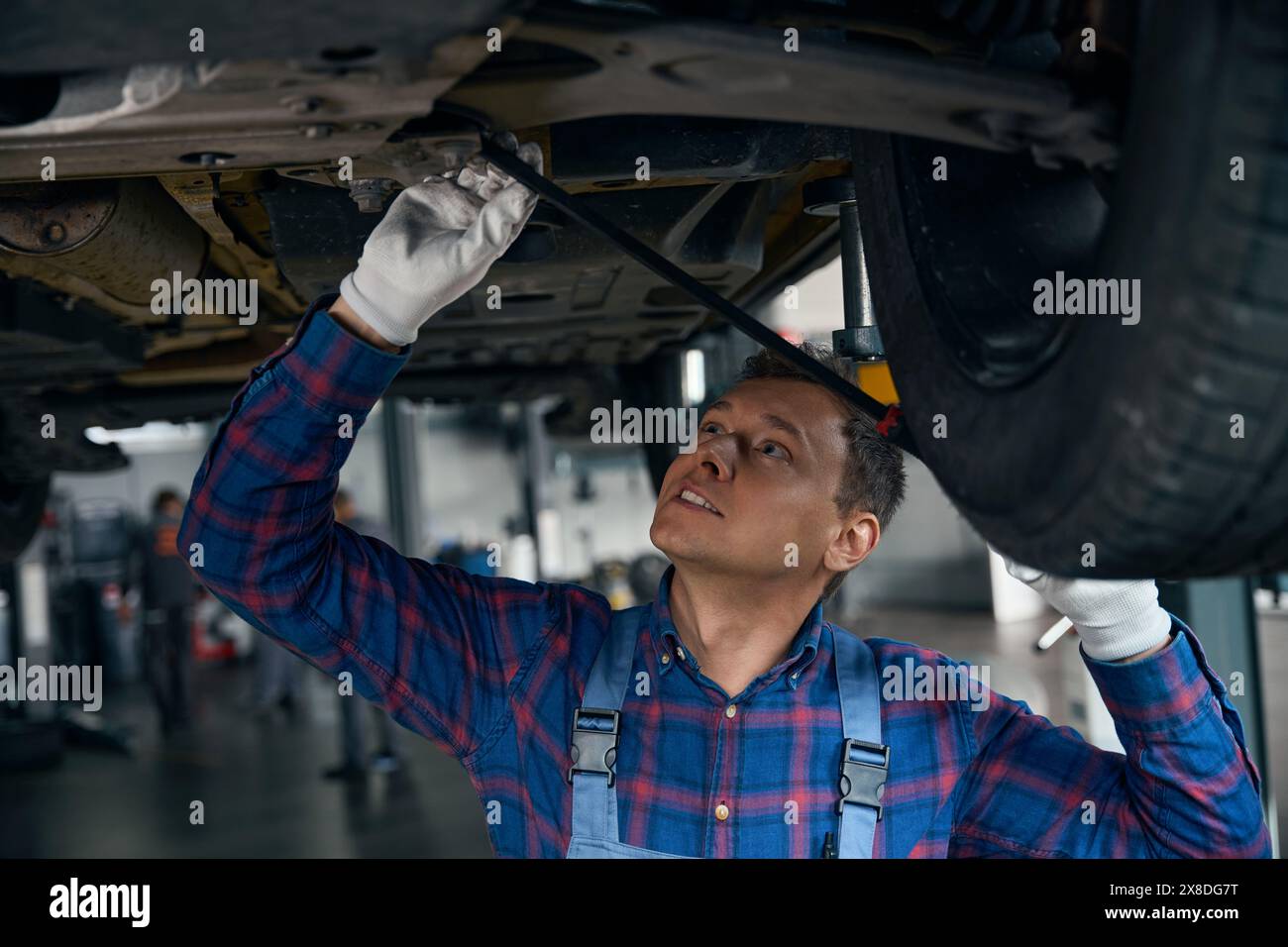 Man performing maintenance on chassis of machine Stock Photo - Alamy