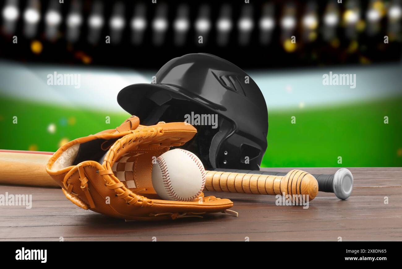 Baseball bats, glove, helmet and ball on wooden table at stadium ...