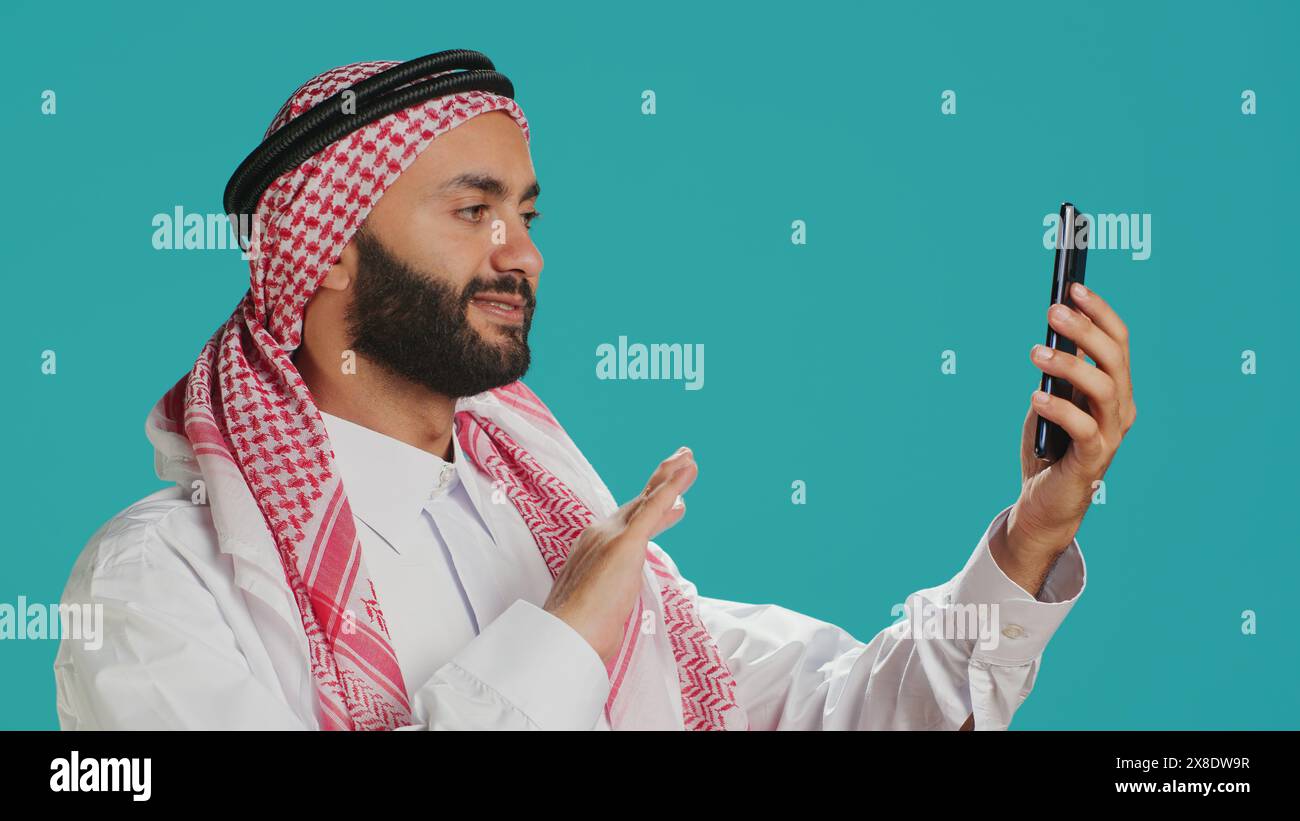 Arabic person engages in online conversation on his mobile device ...