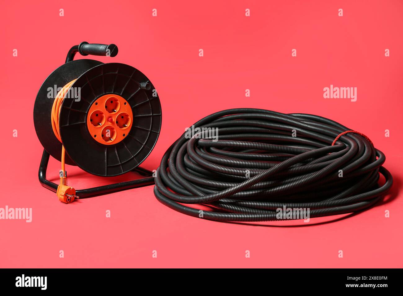 Extension cable reel and flexible conduit tube on red background Stock ...