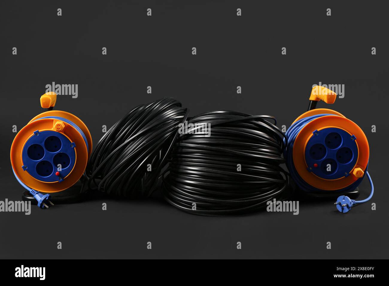 Rolled wires and extension cable reels on black background Stock Photo ...