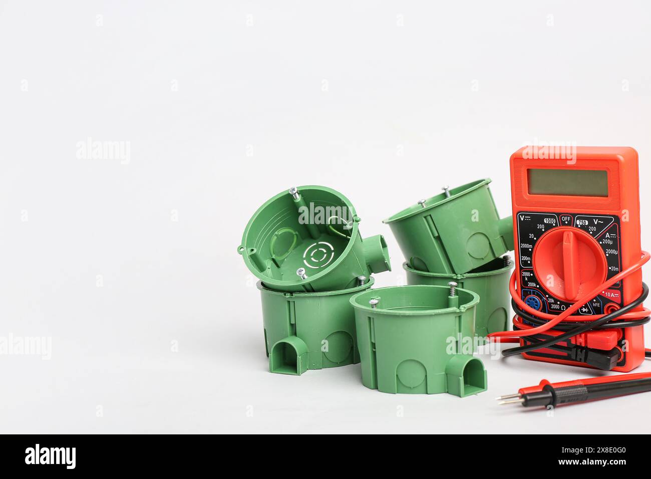 Set of plastic socket boxes and multimeter on light background Stock ...