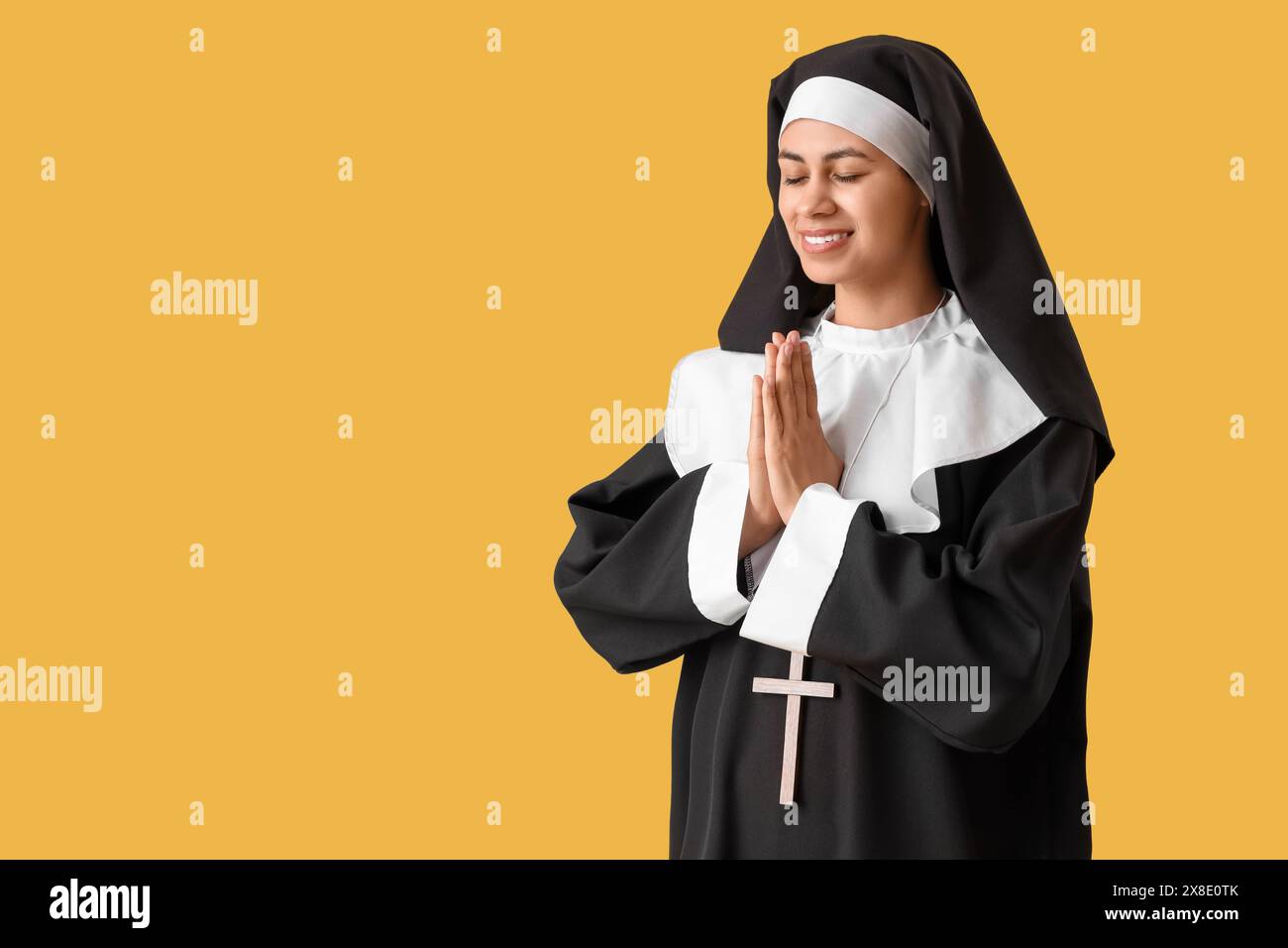 Young nun praying on yellow background Stock Photo - Alamy