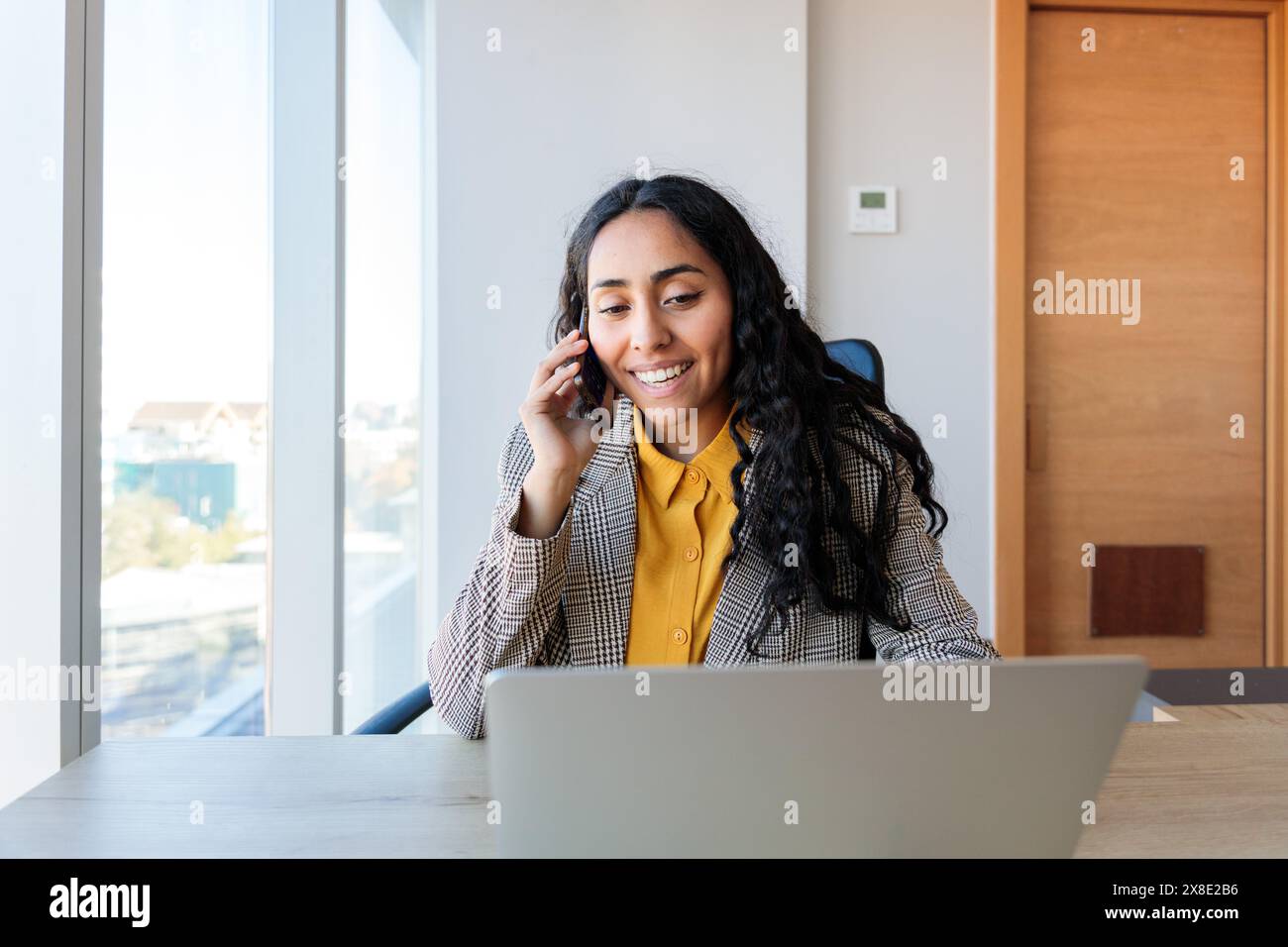 Multitasking young latin executive woman working with laptop and phone ...