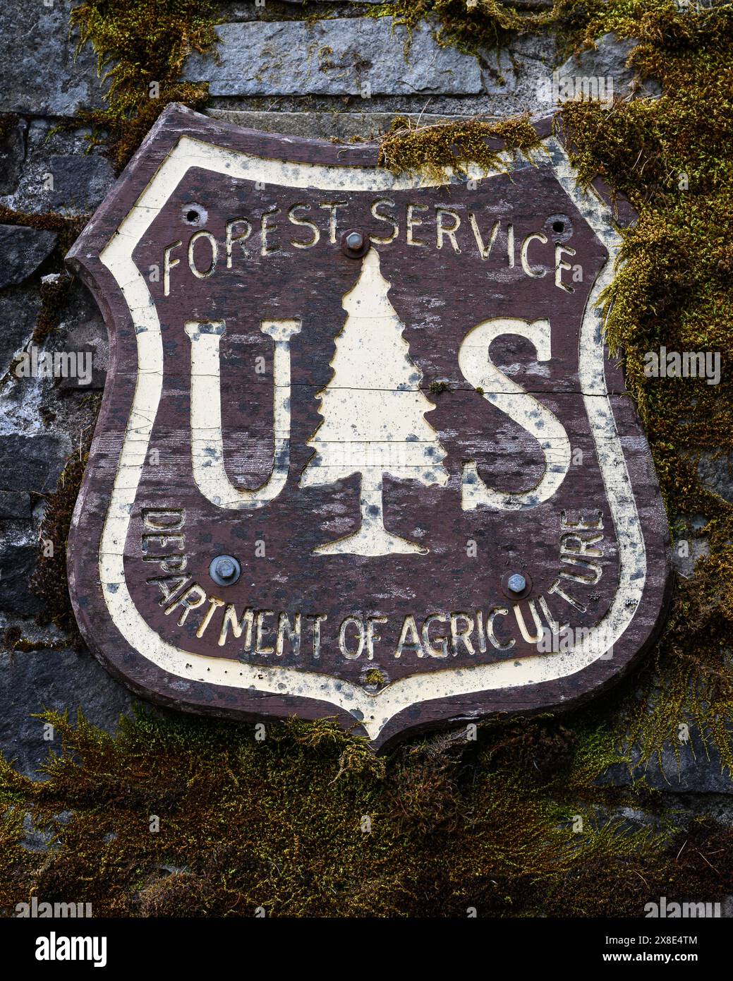 Oregon, US - April 24, 2024; Weathered wooden sign in closeup with moss ...