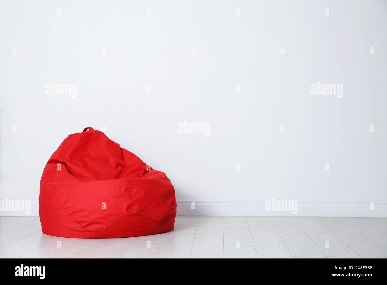 Red bean bag chair near white wall in room Stock Photo - Alamy