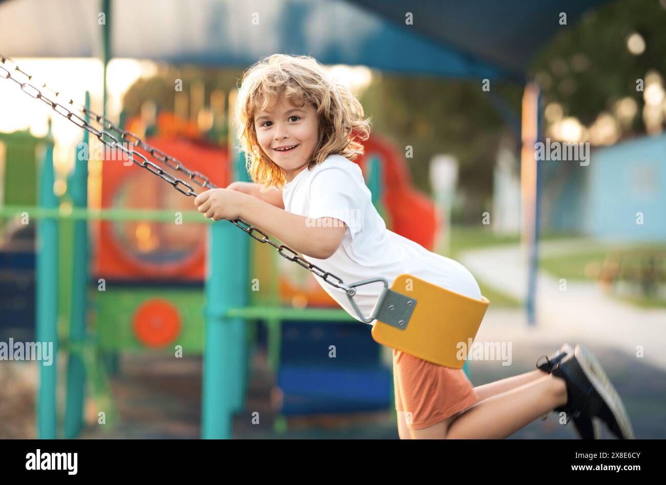 Kid on swing. Little child having fun on a swing outdoor. Summer playground. Kid swinging high ...