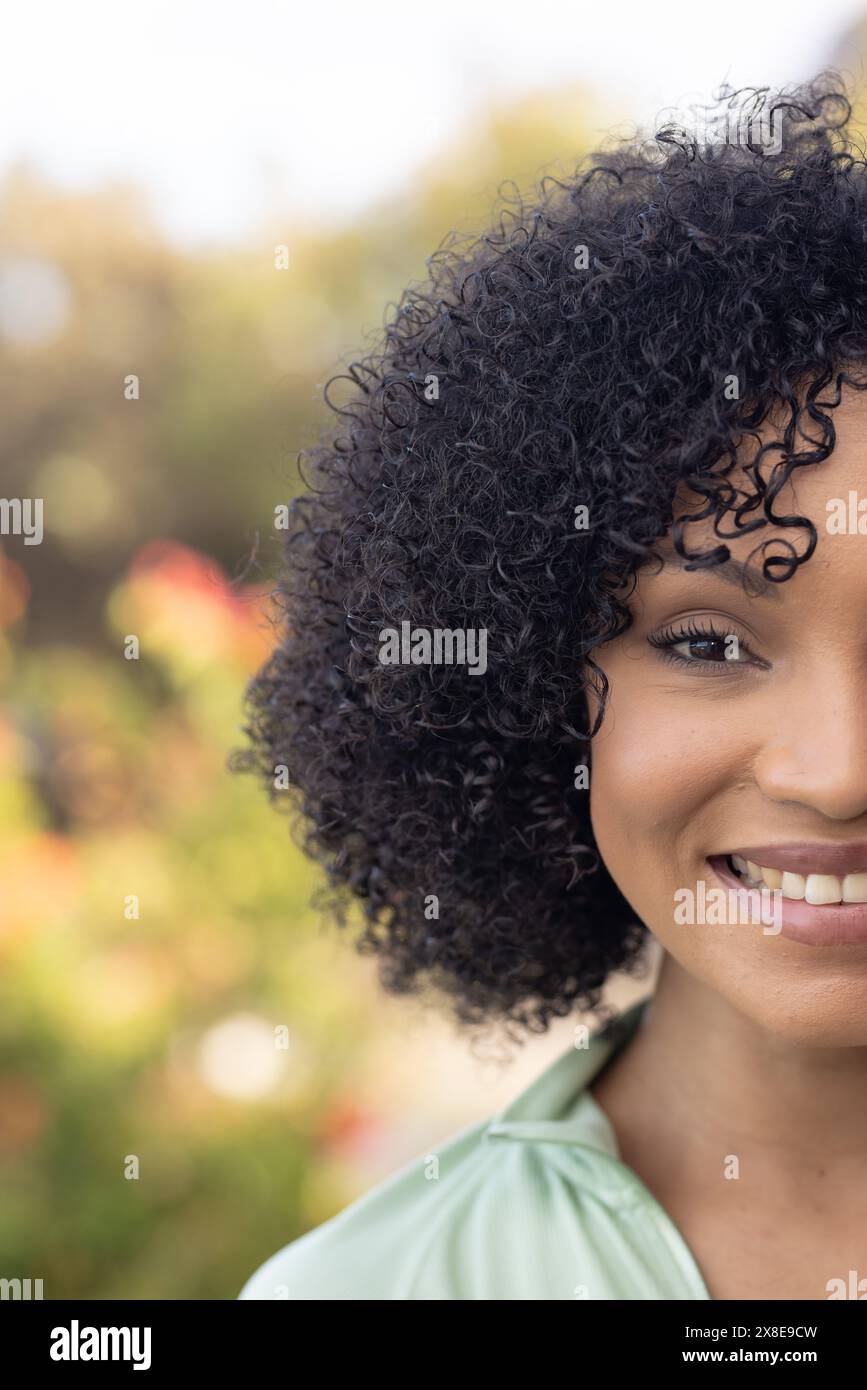 A biracial woman outdoors, wearing light green blouse, smiling. With ...