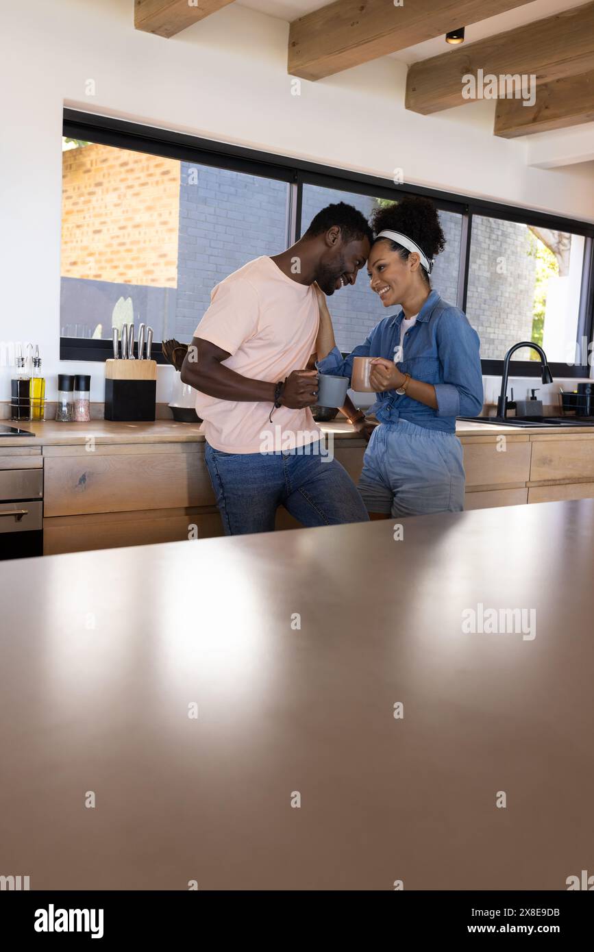 A diverse couple, sharing coffee at home, enjoying warm moment, copy ...