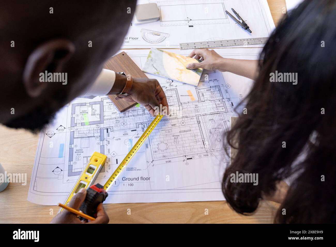 Diverse team working on architectural drawings at desk with focus and ...