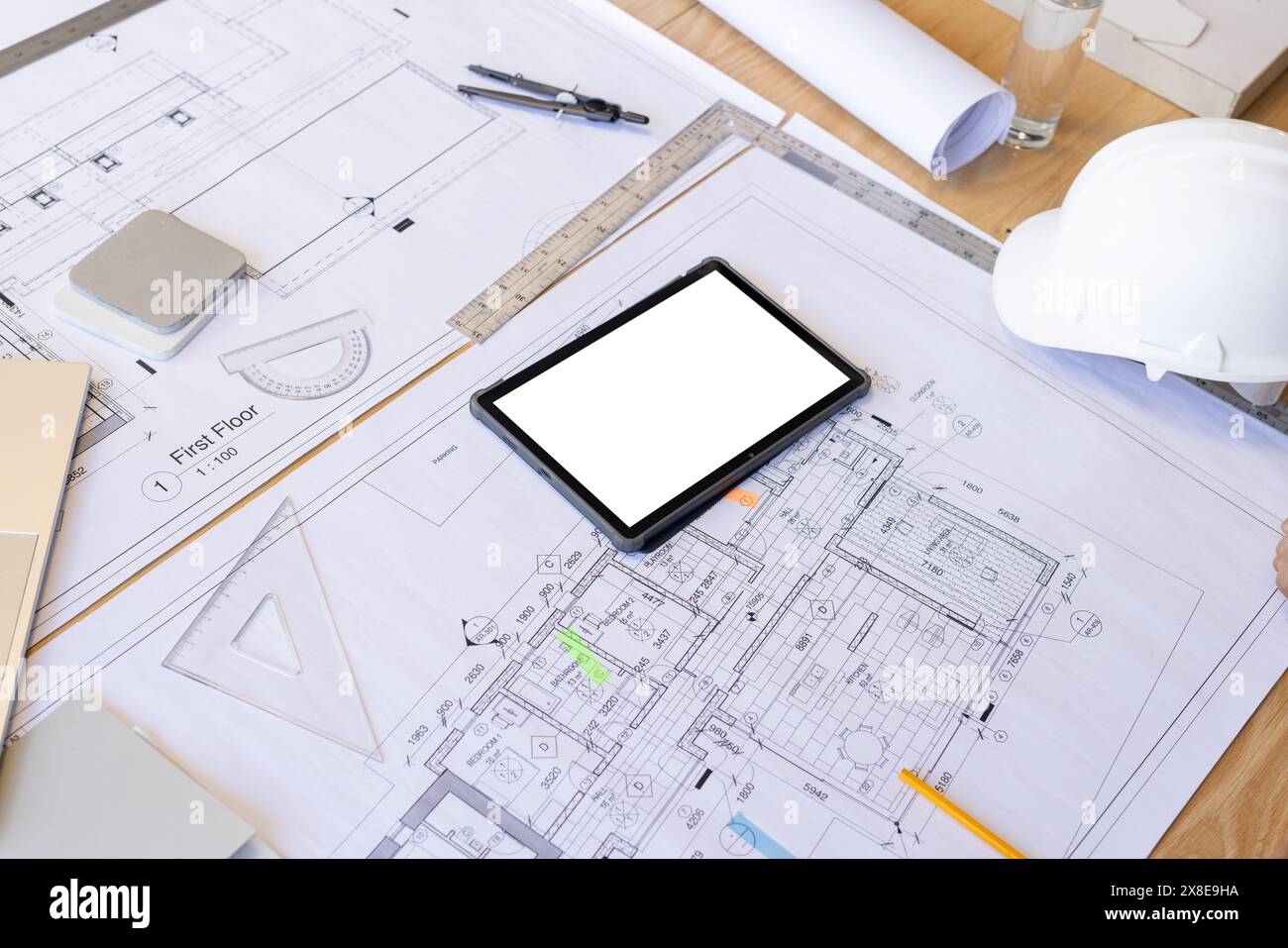 Architectural plans and drawings spread out on table with a tablet in ...