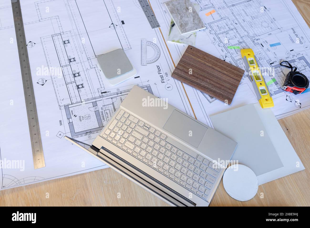 Architectural drawings and materials are spread out on wooden table ...