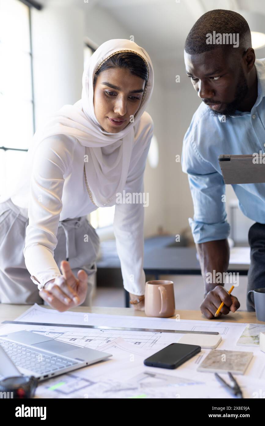 At modern office, diverse team working on architectural plans. Young ...