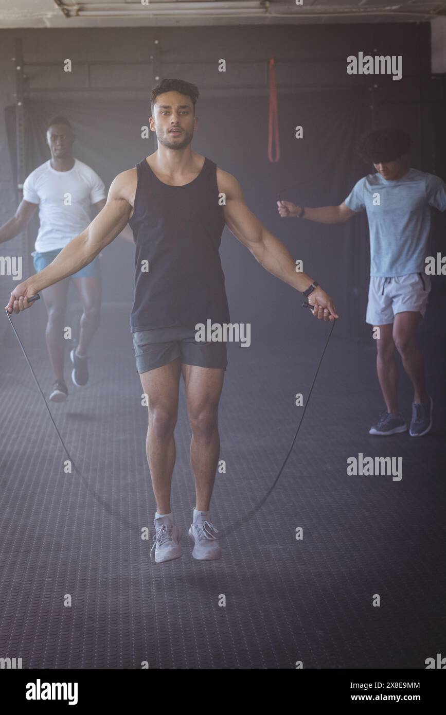 At gym, three fit young diverse men training with jump ropes on rubber ...