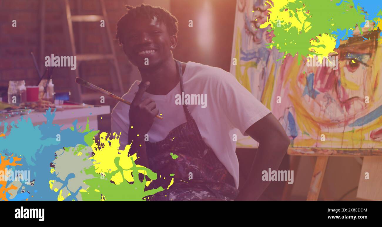 African American male artist, wearing white shirt, painting in studio ...