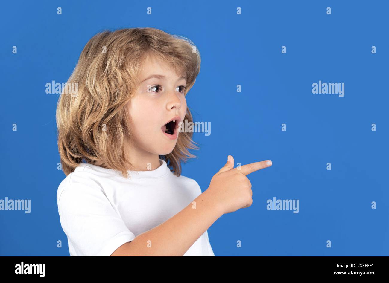 Surprised child looking away, pointing finger on isolated studio ...