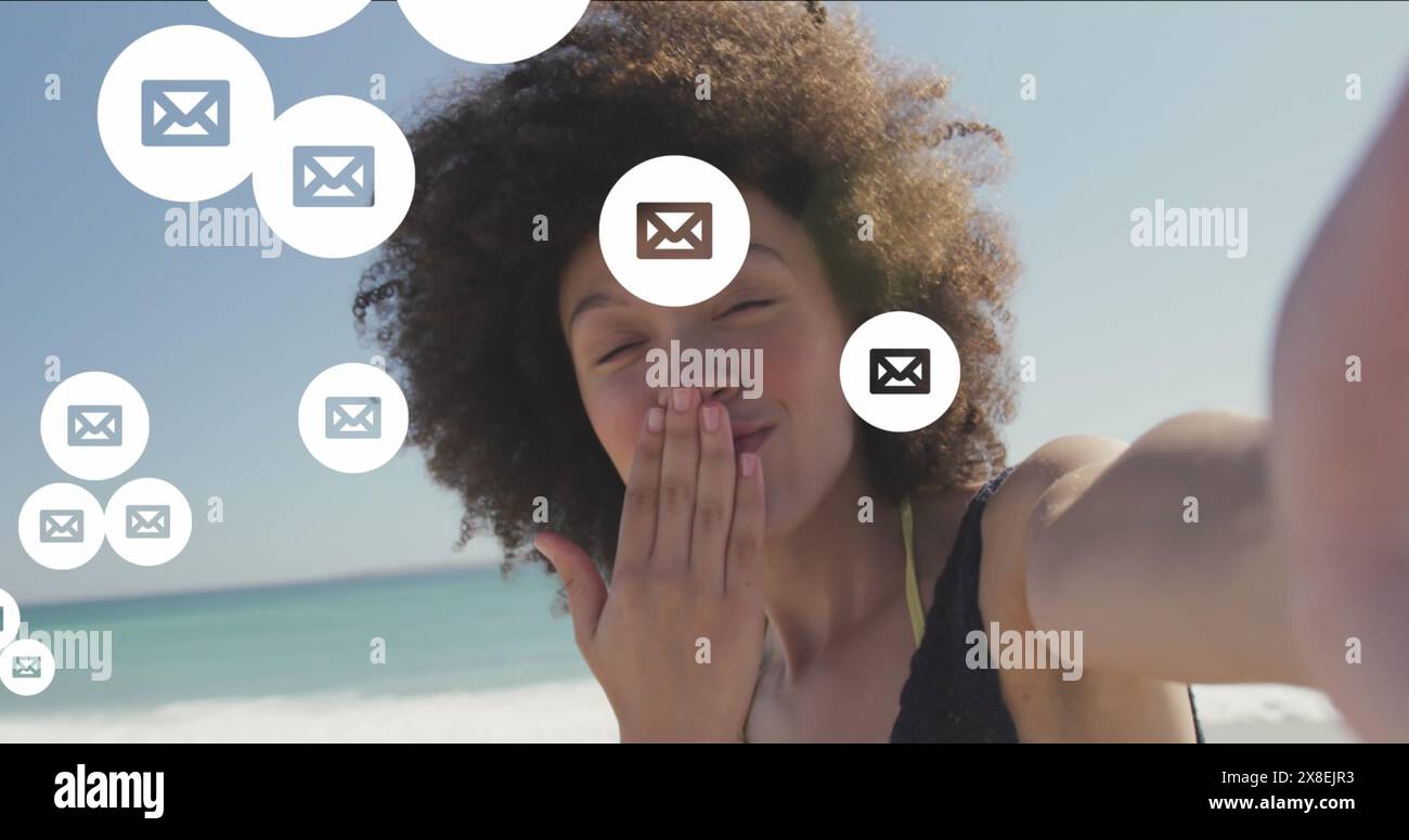 Image Of Envelope Icons Over Biracial Woman Holding Camera And Blowing