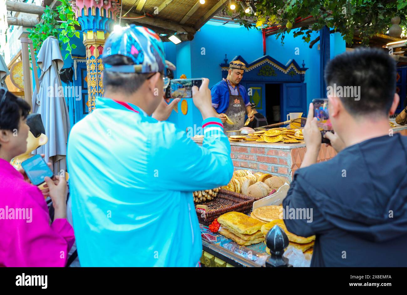 URUMQI, CHINA - MAY 24, 2024 - Tourists watch the making of naan bread ...