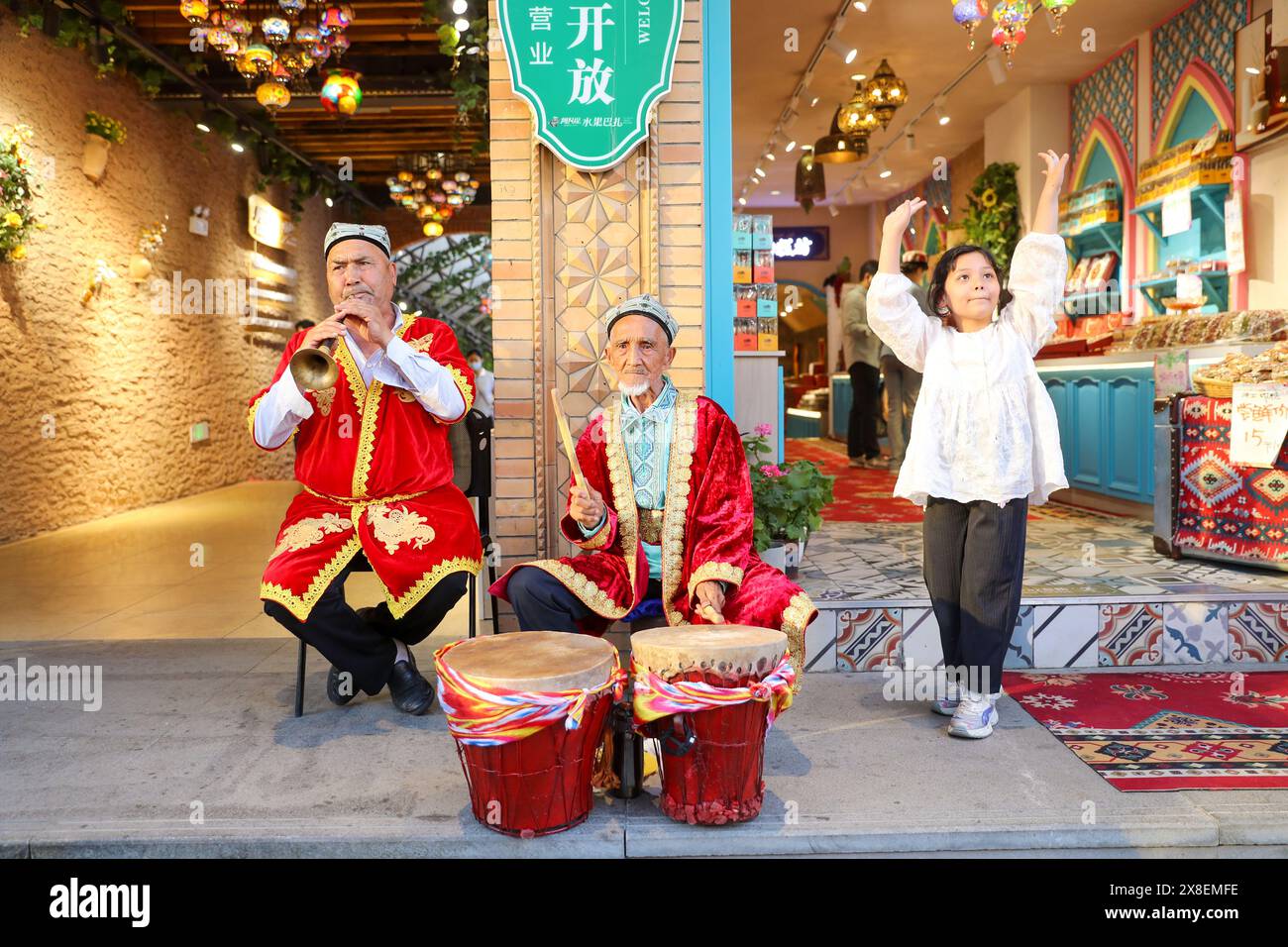URUMQI, CHINA - MAY 24, 2024 - A girl dances as two elderly people play ...