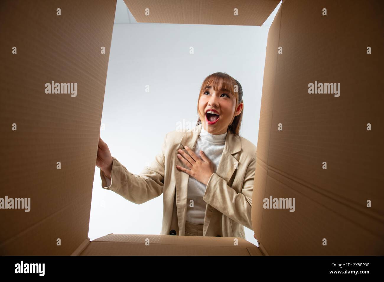 Smiling young woman opening a carton box, relocation and unpacking ...