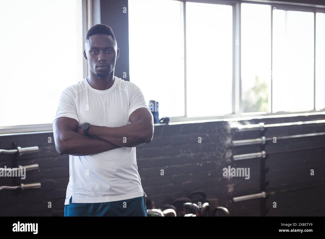 Strong and fit African American man standing with arms crossed at gym ...