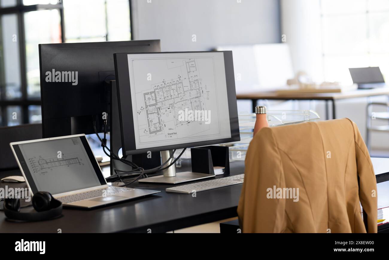 Office desk showing computer screens with architectural plans and ...