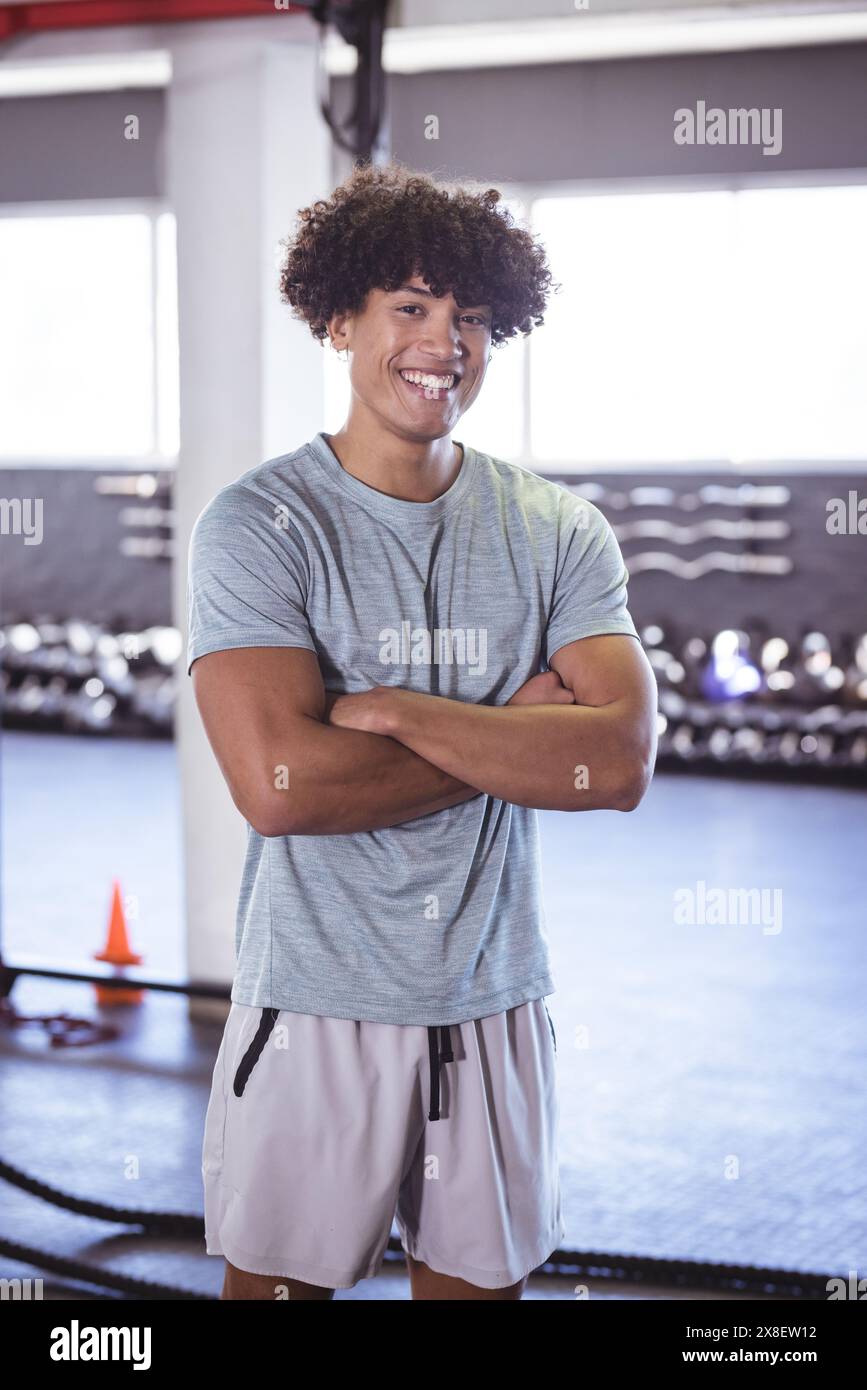 Young biracial man at gym with strong and fit physique standing with ...