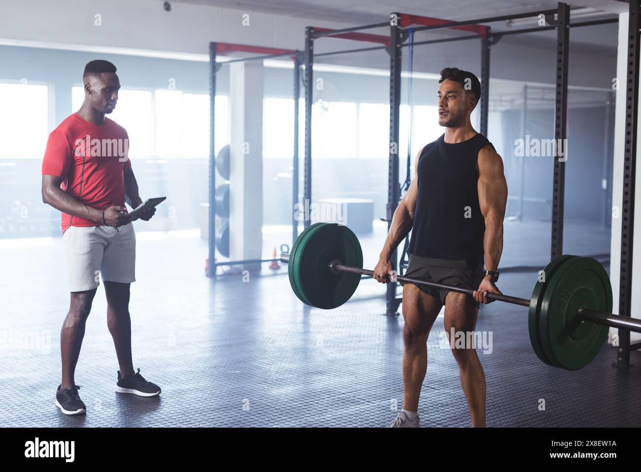 At gym, diverse men including African American man watch biracial man ...