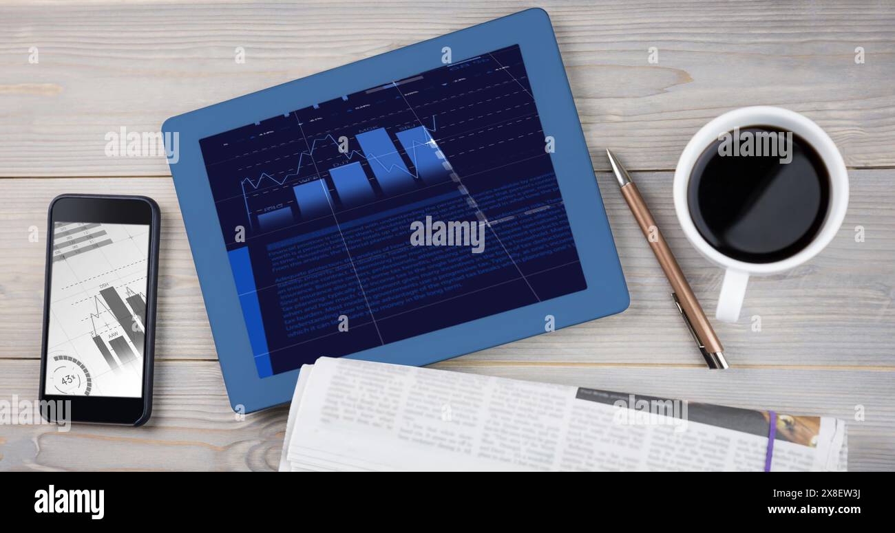 Devices on table displaying financial charts, alongside a coffee cup ...